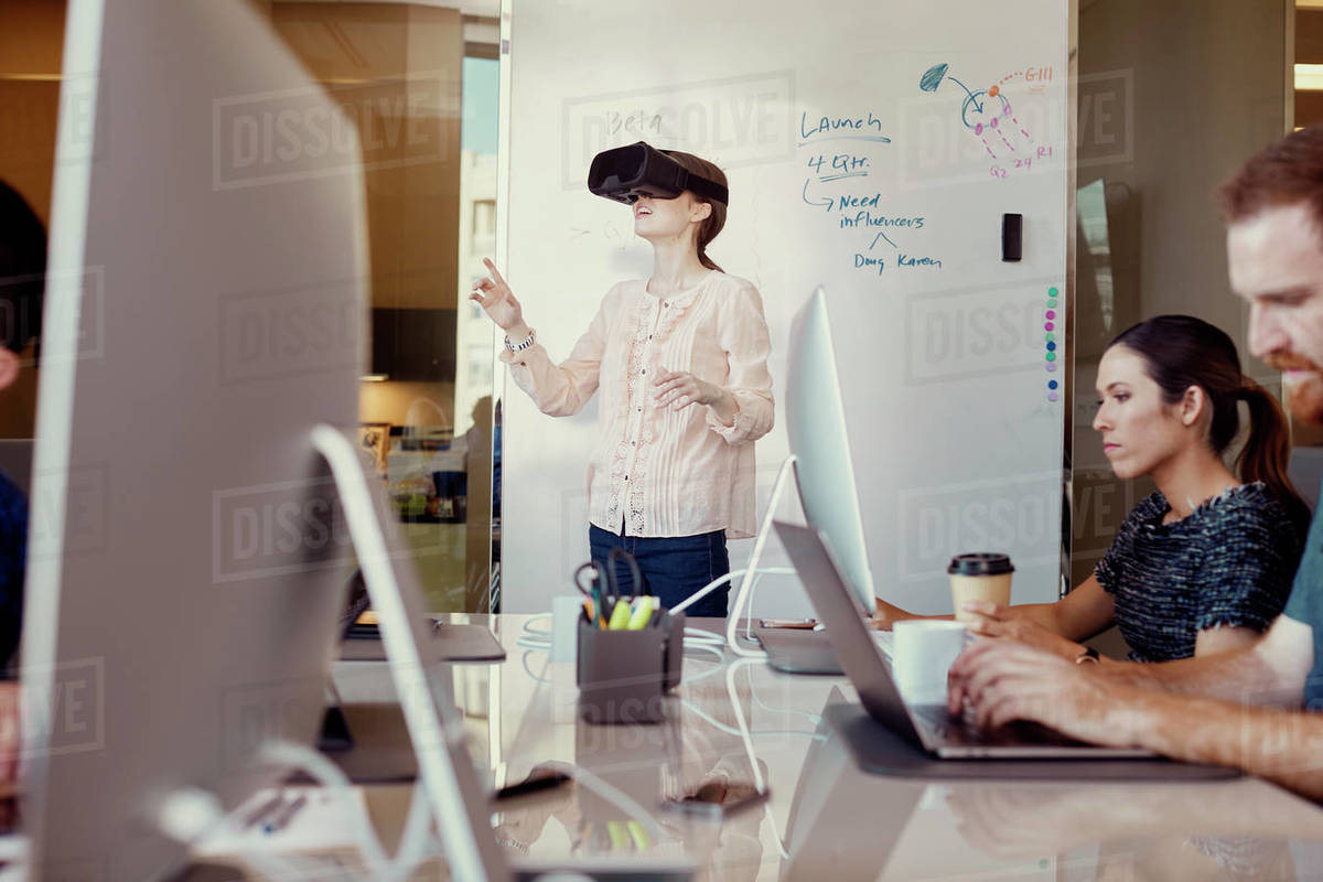 Co-Workers working on computer in office while woman is using Virtual ...