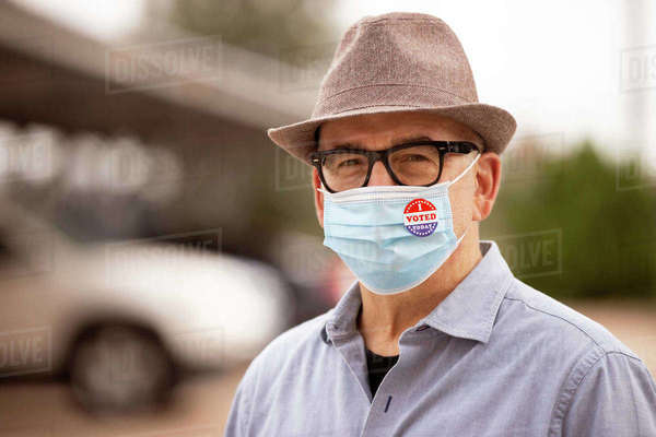 Older Caucasian male with glasses and fedora, wearing a mask and an I ...