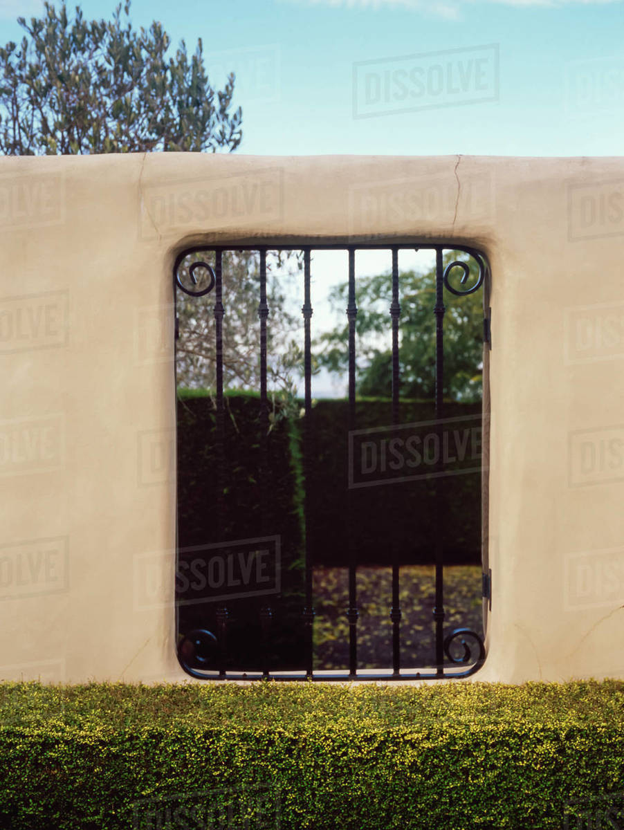 Barred window in outside wall looking through to garden - Stock Photo ...