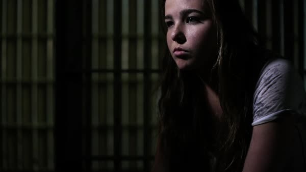 Caucasian teenage girl sitting in dark jail cell - HD Royalty-free ...