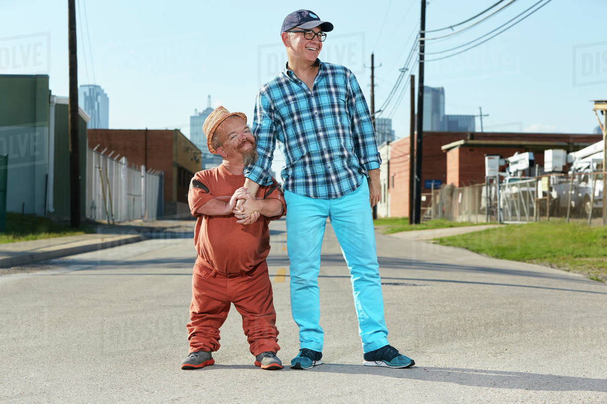 Portrait of male dwarf little person hugging his friend, standing in ...