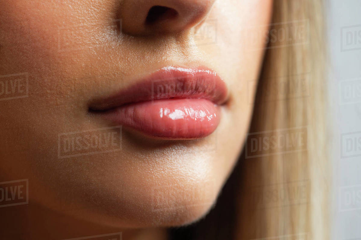 Close up of a young Hispanic woman's lip with glossy lipstick ...