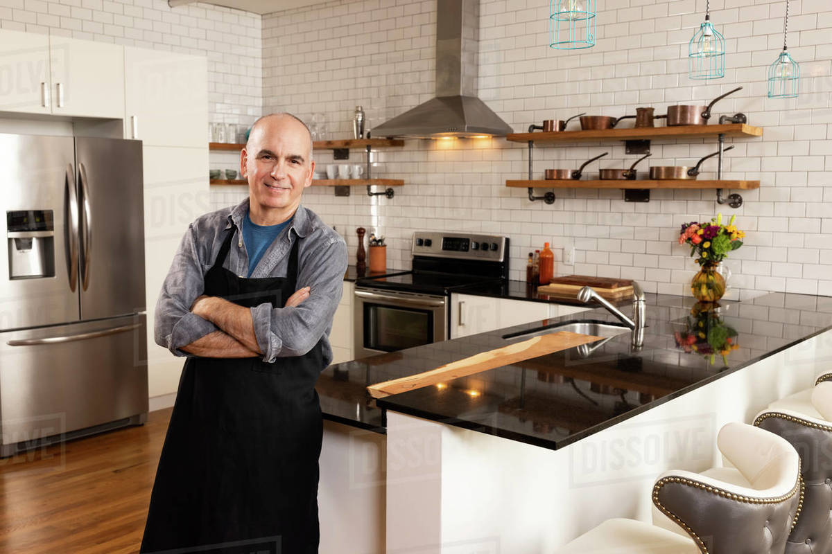Portrait of man standing in kitchen lookin into camera with confidence ...