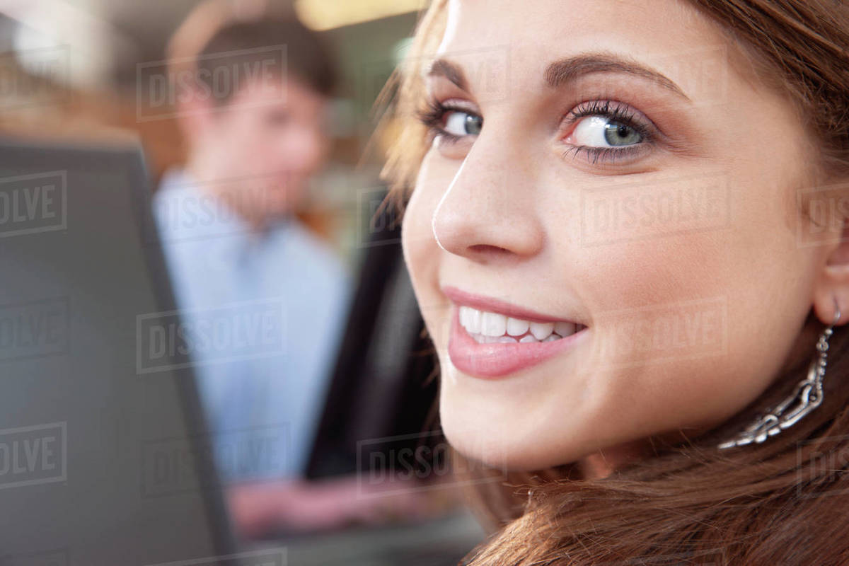 Portrait of woman looking over shoulder, smiling at camera while on ...