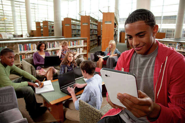 Group of students using laptop at table in college library, one student ...