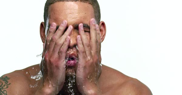 Shirtless man leaning over sink splashing water over his face - Stock ...