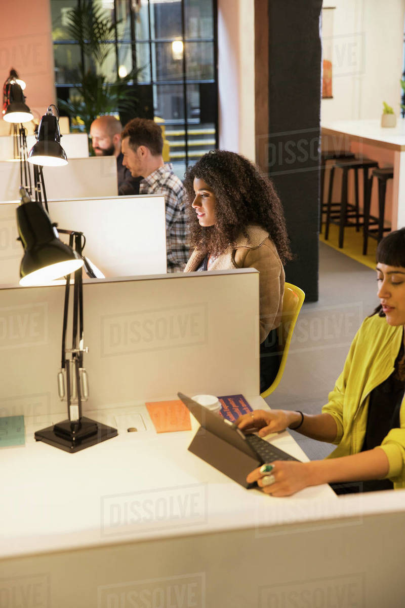 Group of young adults at individual workstations in co-working space ...