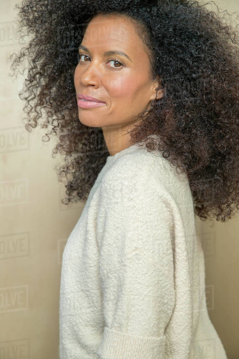 Portrait of a mixed race middle-aged woman looking back over her shoulder towards camera ...