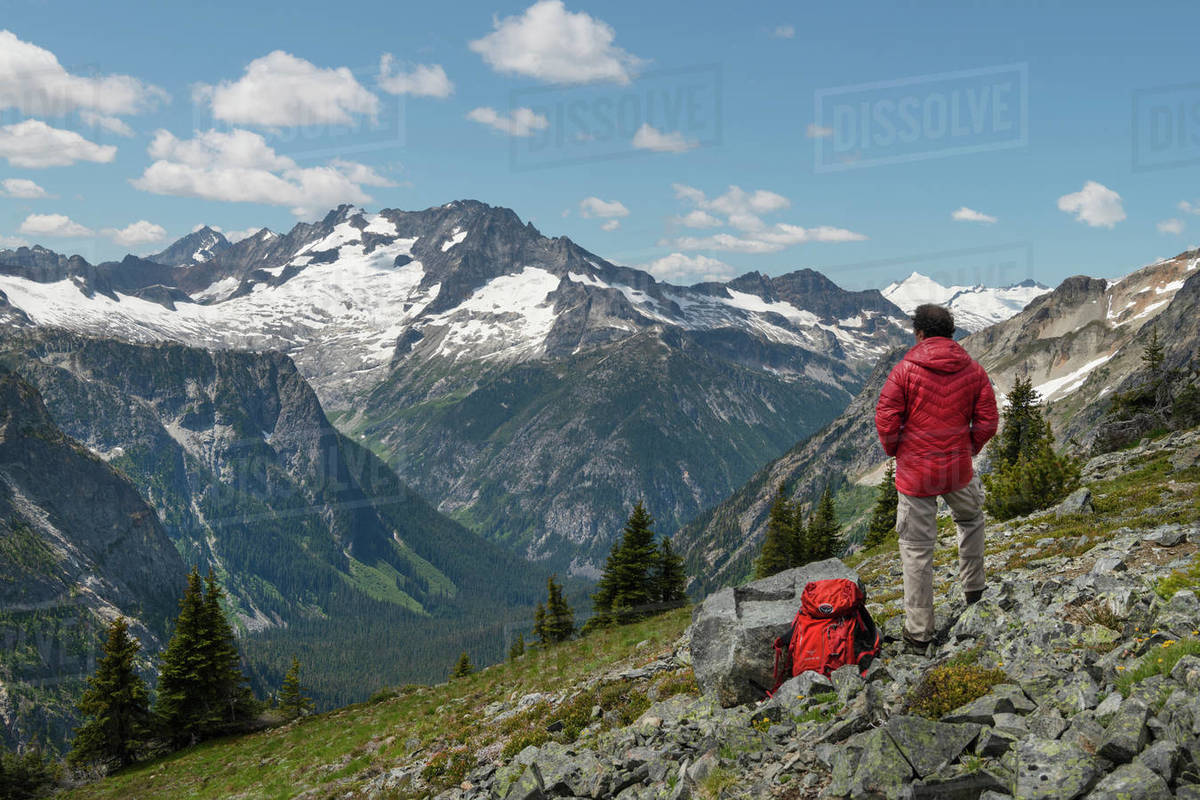 Adult male hiker with red jacket and backpack relaxing on Ragged Ridge ...