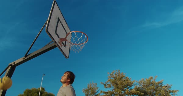 Male basketball player slam dunking on an outdoor basketball court ...