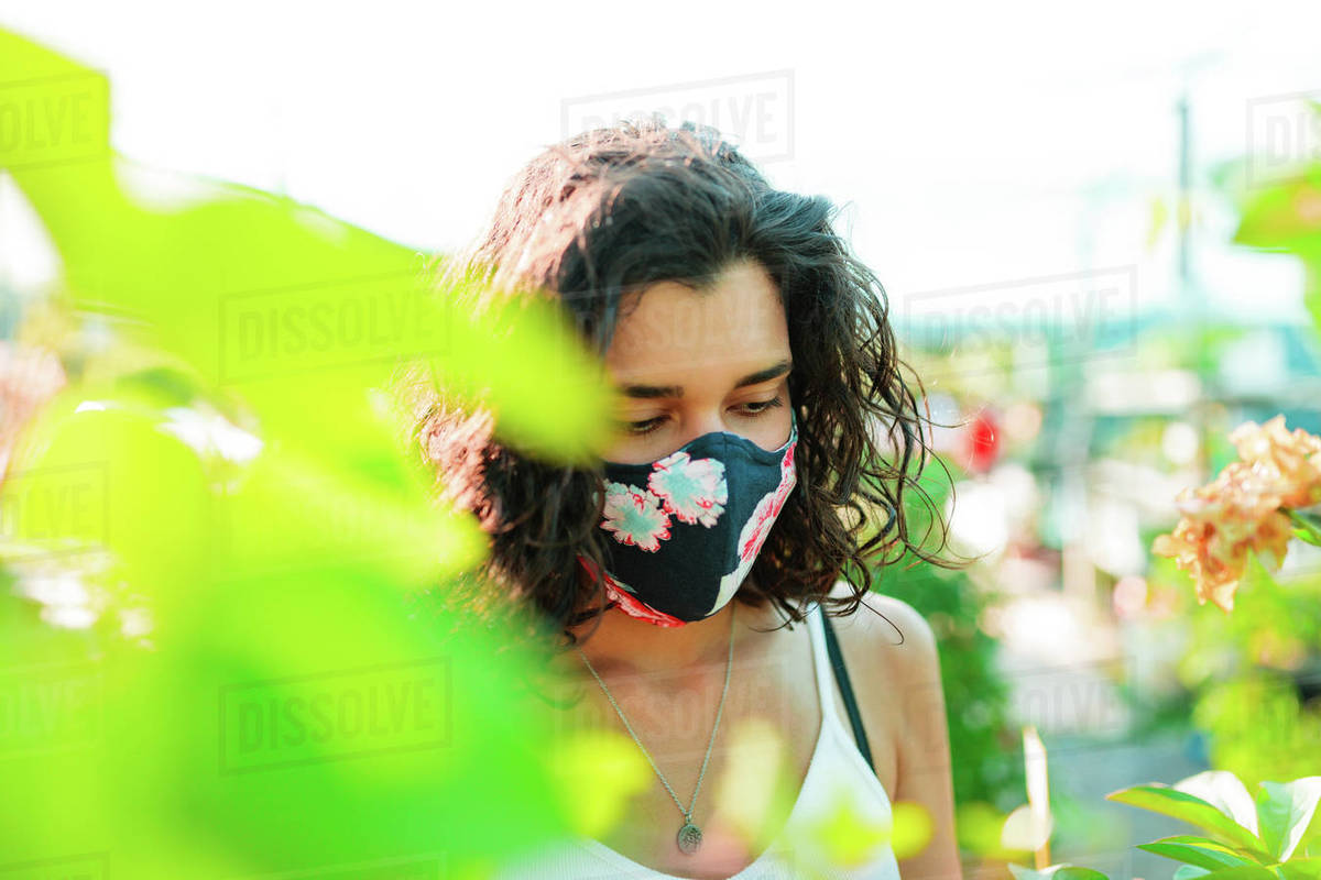 Woman with face mask gardening in greenhouse. People outdoor activities ...