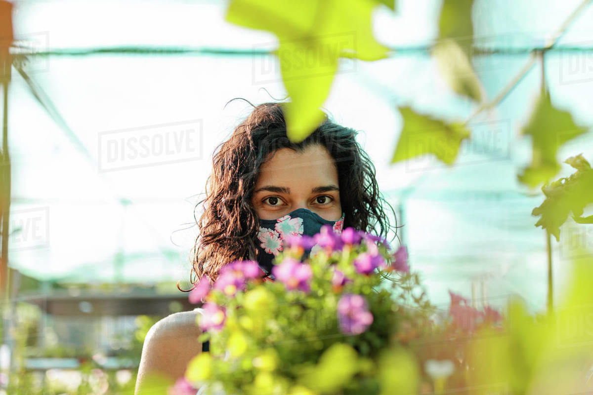Woman with face mask gardening in greenhouse. People outdoor activities ...