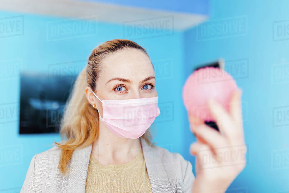Woman wearing surgical mask with covid 19 model in her hand - Stock ...
