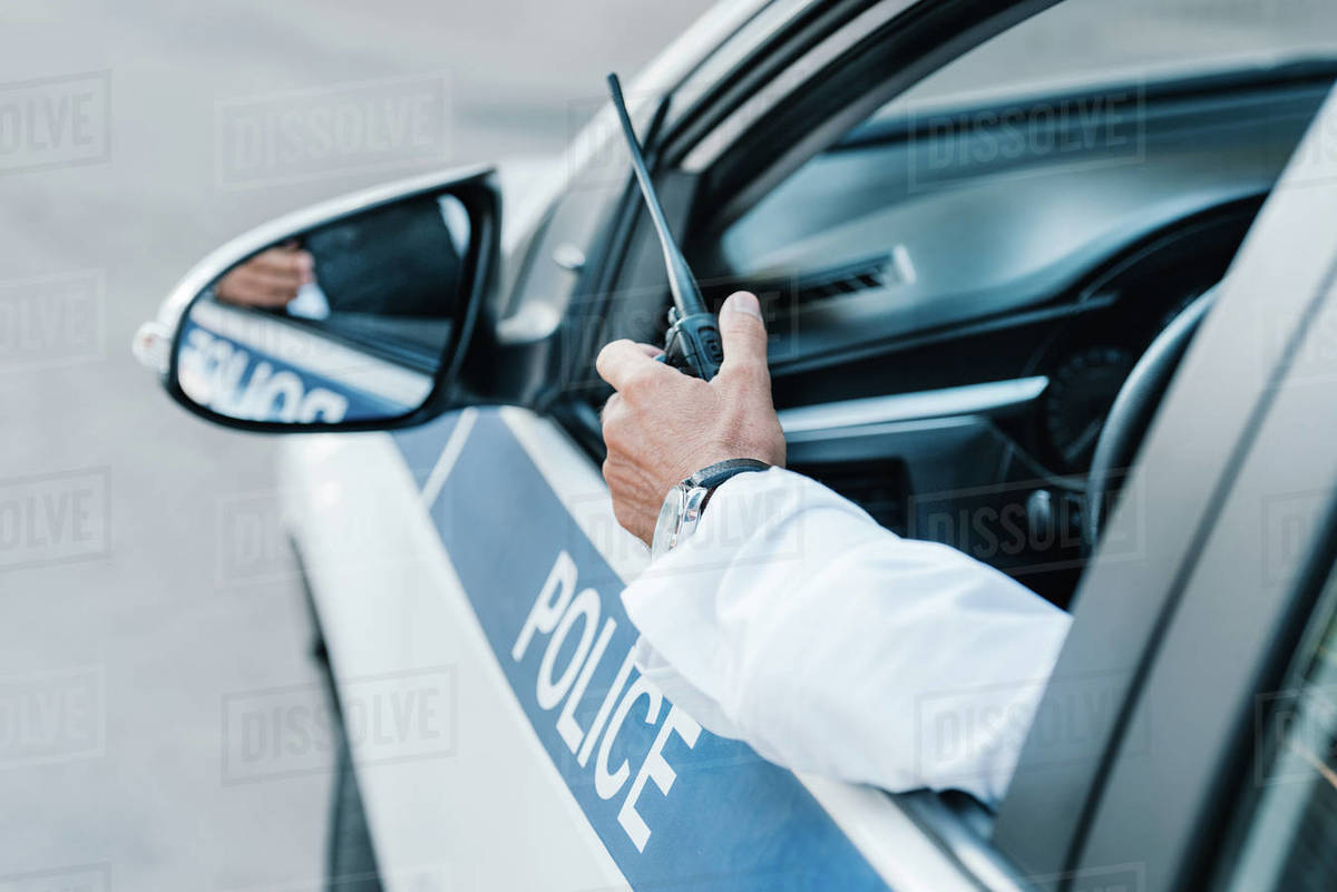 cropped image of male police officer holding radio set in car - Royalty ...