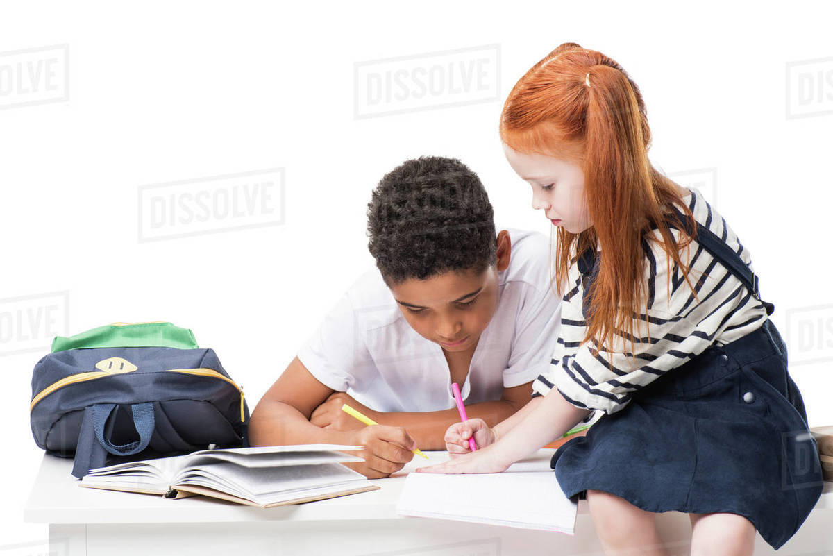 Cute focused multiethnic schoolkids studying together isolated on white ...
