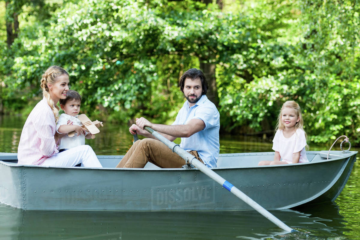 Side view of young family riding boat on river at park - Royalty-free ...