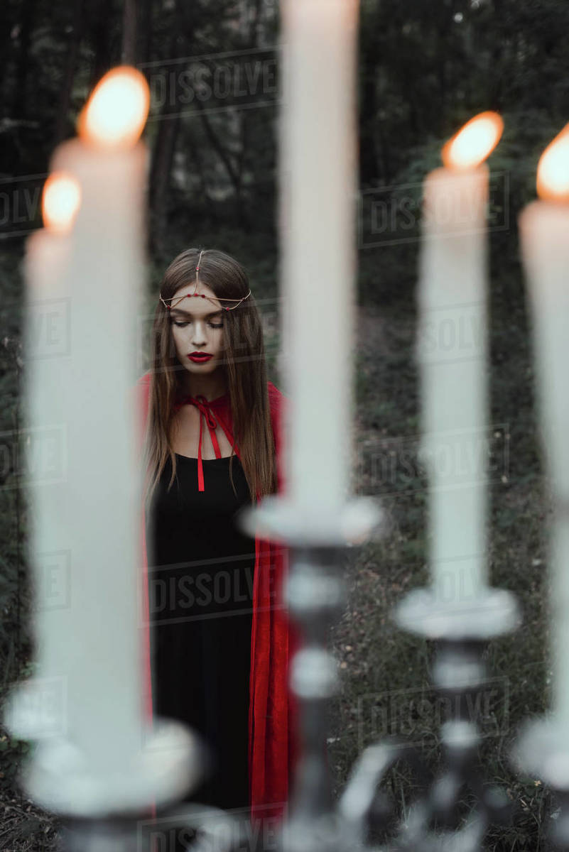 Selective focus of mystic girl and candelabrum with flaming candles on ...