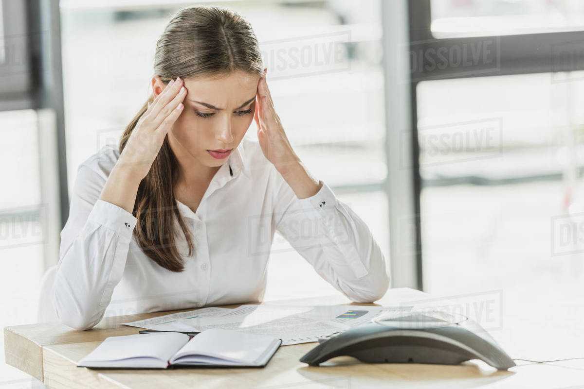 Confused young businesswoman doing paperwork at office - Royalty-free ...