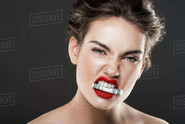 Attractive angry woman holding money in teeth, isolated on grey - Stock ...