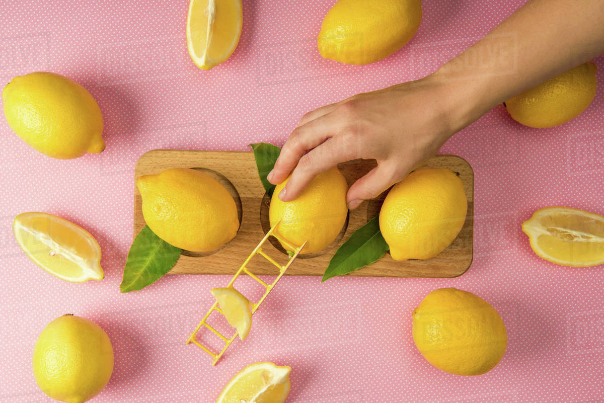 Cropped view of woman taking lemon with little ladder from wooden board ...