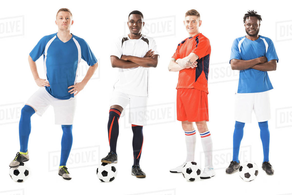 confident young multiethnic soccer players standing with balls and ...