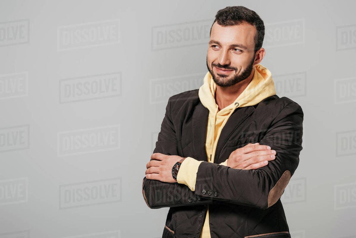 Smiling male model posing with crossed arms isolated on grey background ...