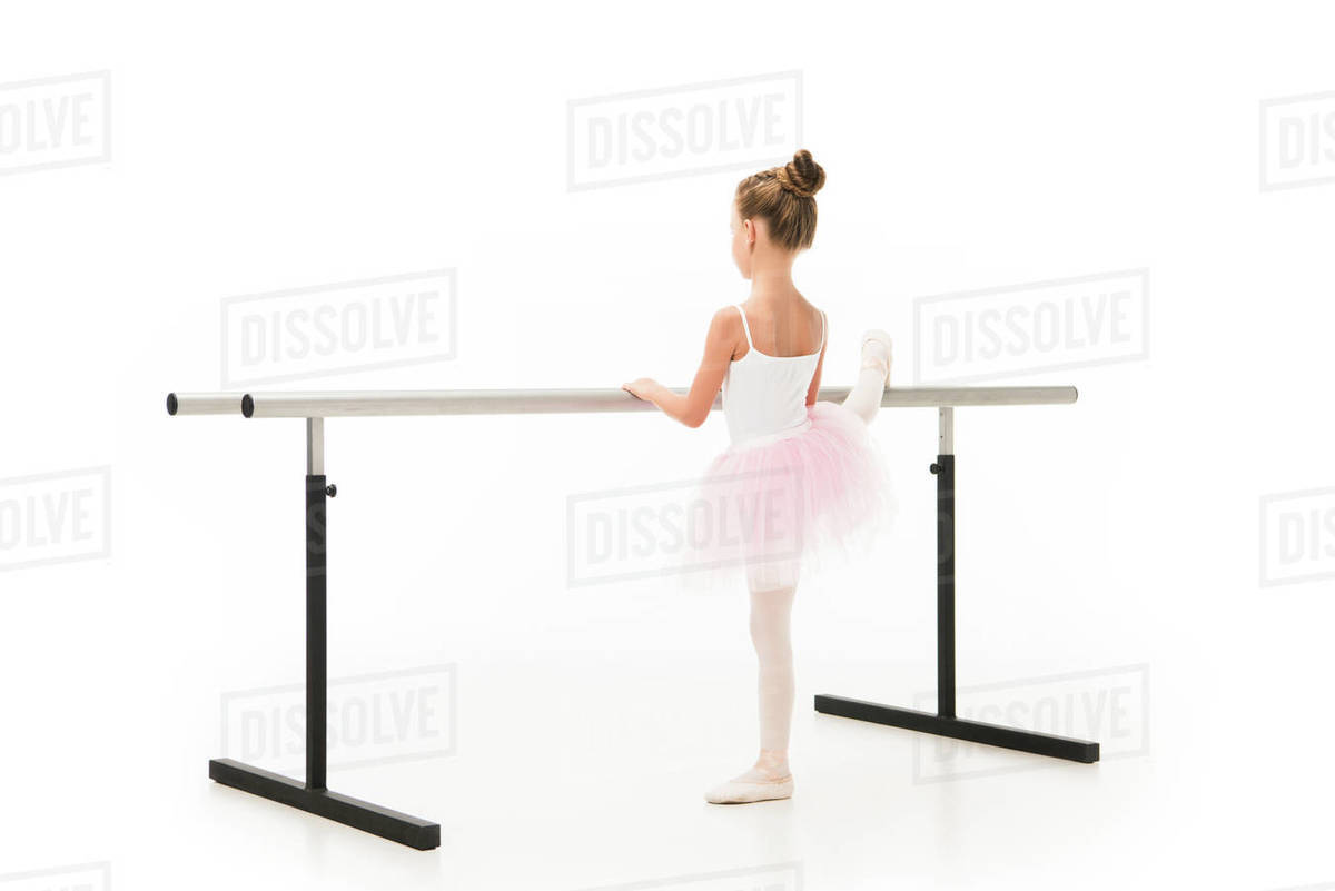 Rear view of little ballerina in tutu and pointe shoes exercising at ...