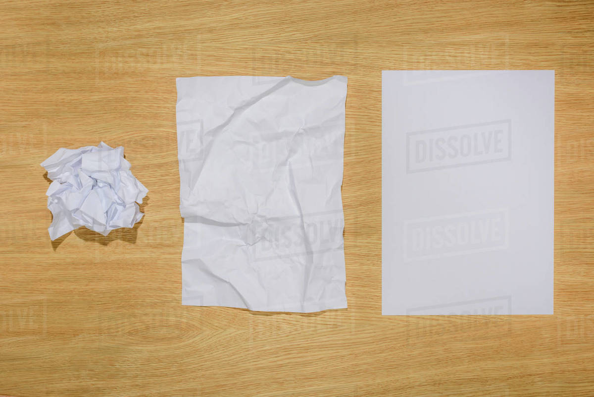 Top view of crumpled papers and blank white paper on wooden table ...