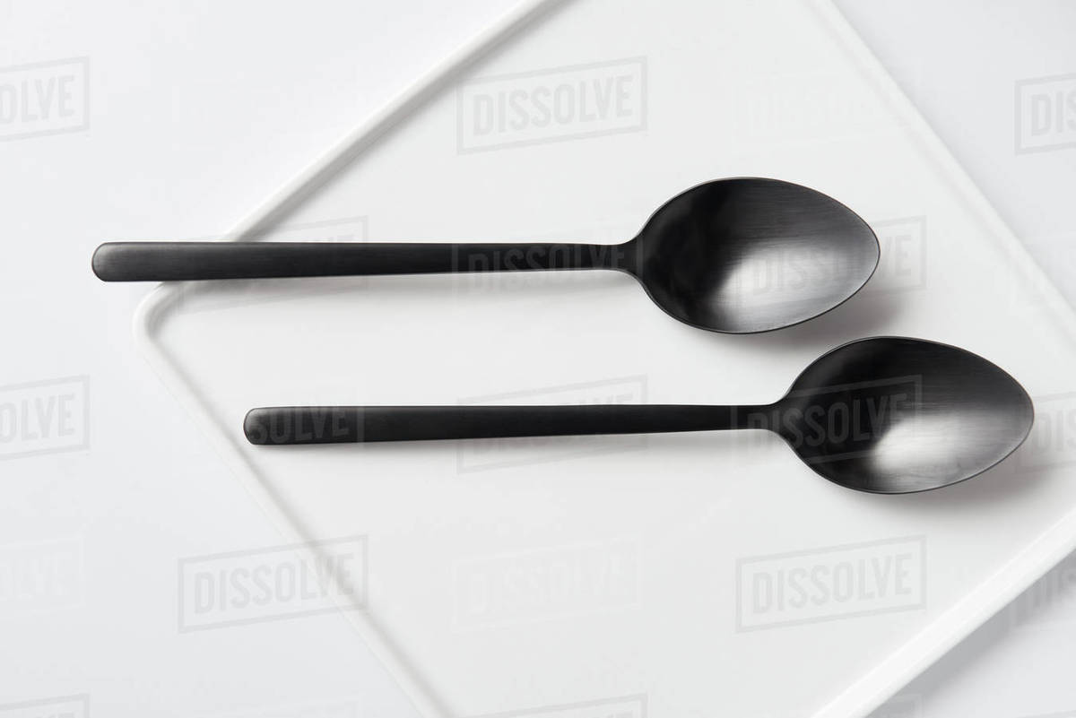 Top view of two spoons and plate on white table, minimalistic concept ...