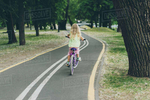 Back view of blond child riding bicycle on road in park - Stock Photo ...