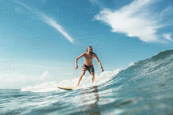Shirtless male surfer riding waves in ocean at Nusa Dua Beach, Bali ...