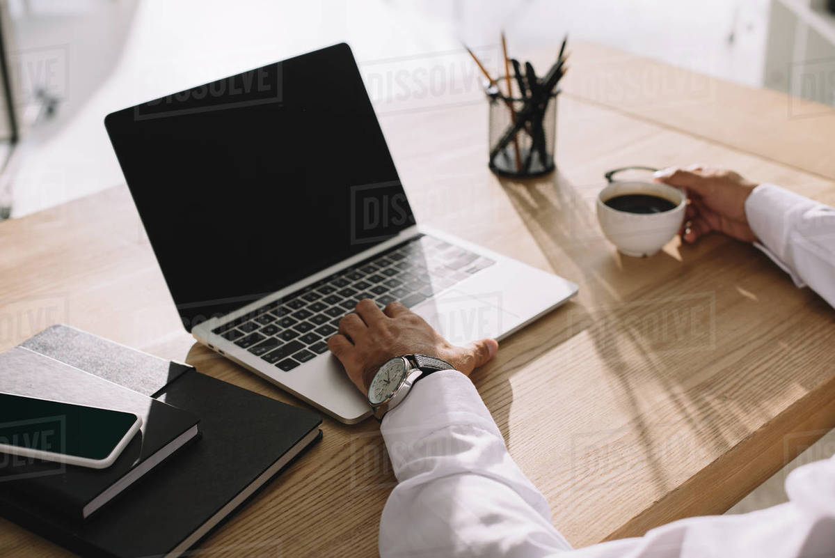 Cropped view of businessman using laptop with blank screen and holding ...
