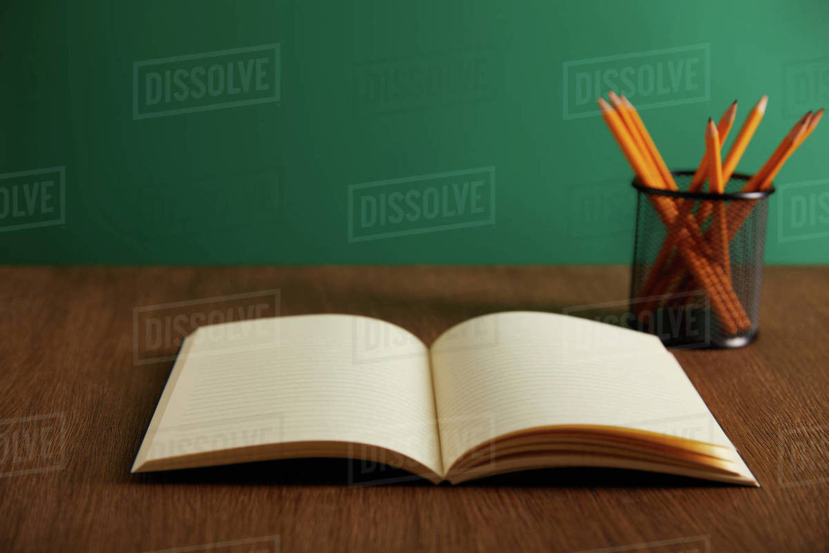 Open book and pencils on wooden table - Stock Photo - Dissolve