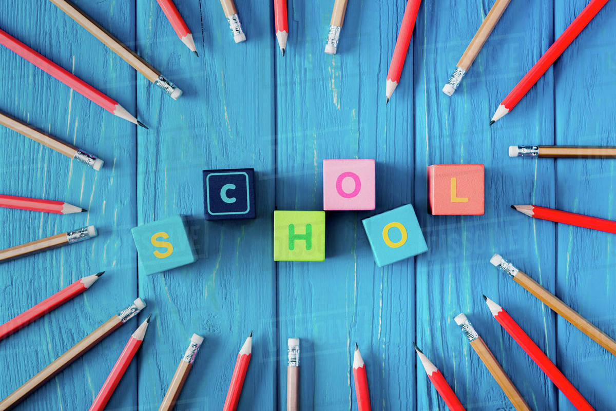 Top view of lettering school made from cubes surrounded by pencils on ...