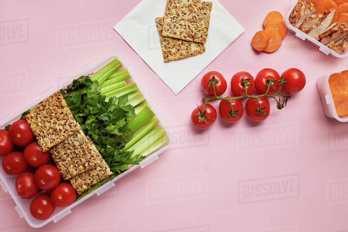 flat lay with healthy food arranged in food containers isolated on pink ...