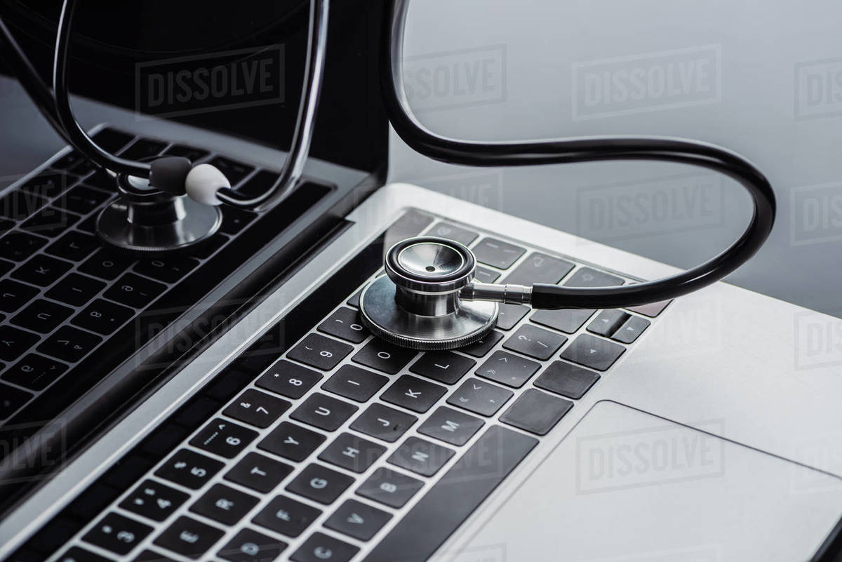 selective focus of stethoscope and laptop with blank screen on grey ...