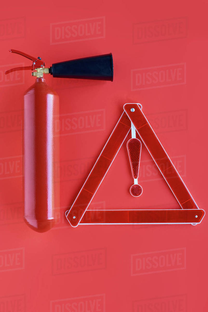 top view of fire extinguisher and warning triangle isolated on red ...