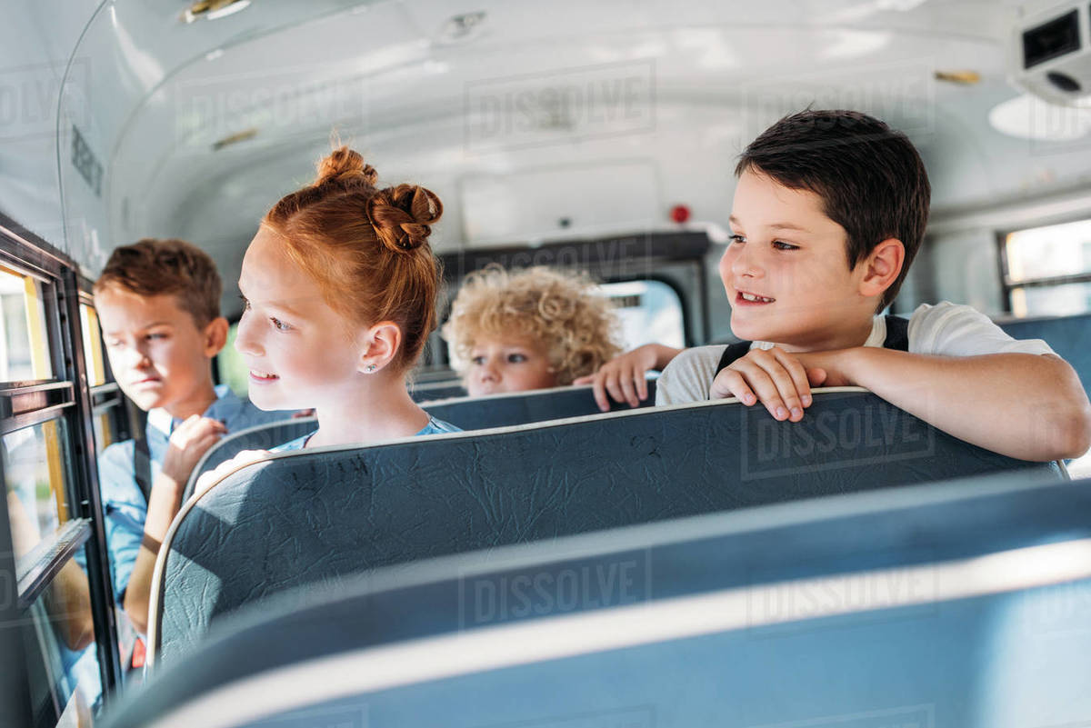 group of pupils riding on school bus and looking through window ...