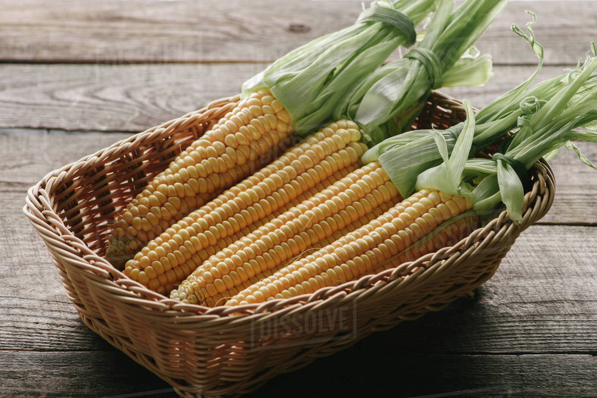 Close up view of ripe corn cobs in basket on wooden surface - Royalty ...