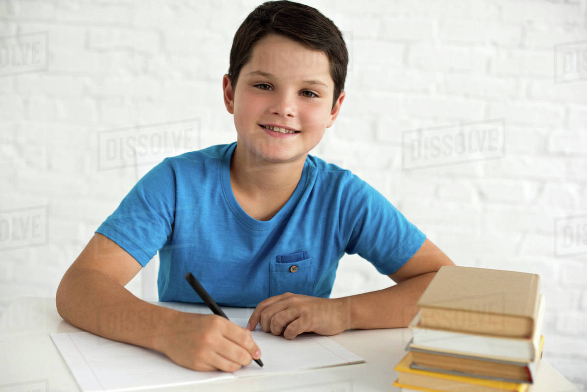 portrait of smiling boy doing homework alone at table at home - Royalty ...