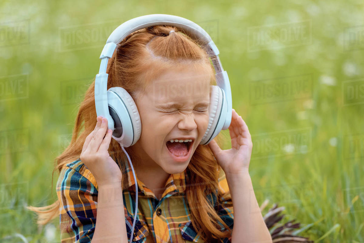 portrait of kid screaming while listening music in headphones with ...