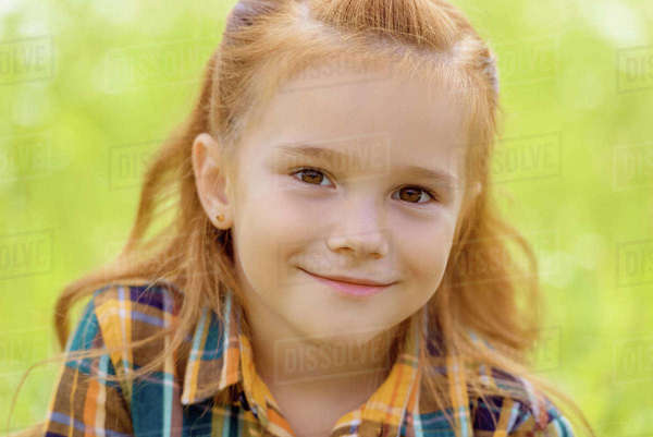 portrait of adorable kid looking at camera with blurred green grass on ...
