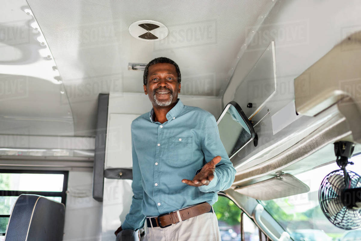 happy mature african american bus driver standing inside bus and ...
