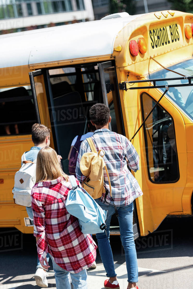 rear view of group of students walking into school bus - Royalty-free ...