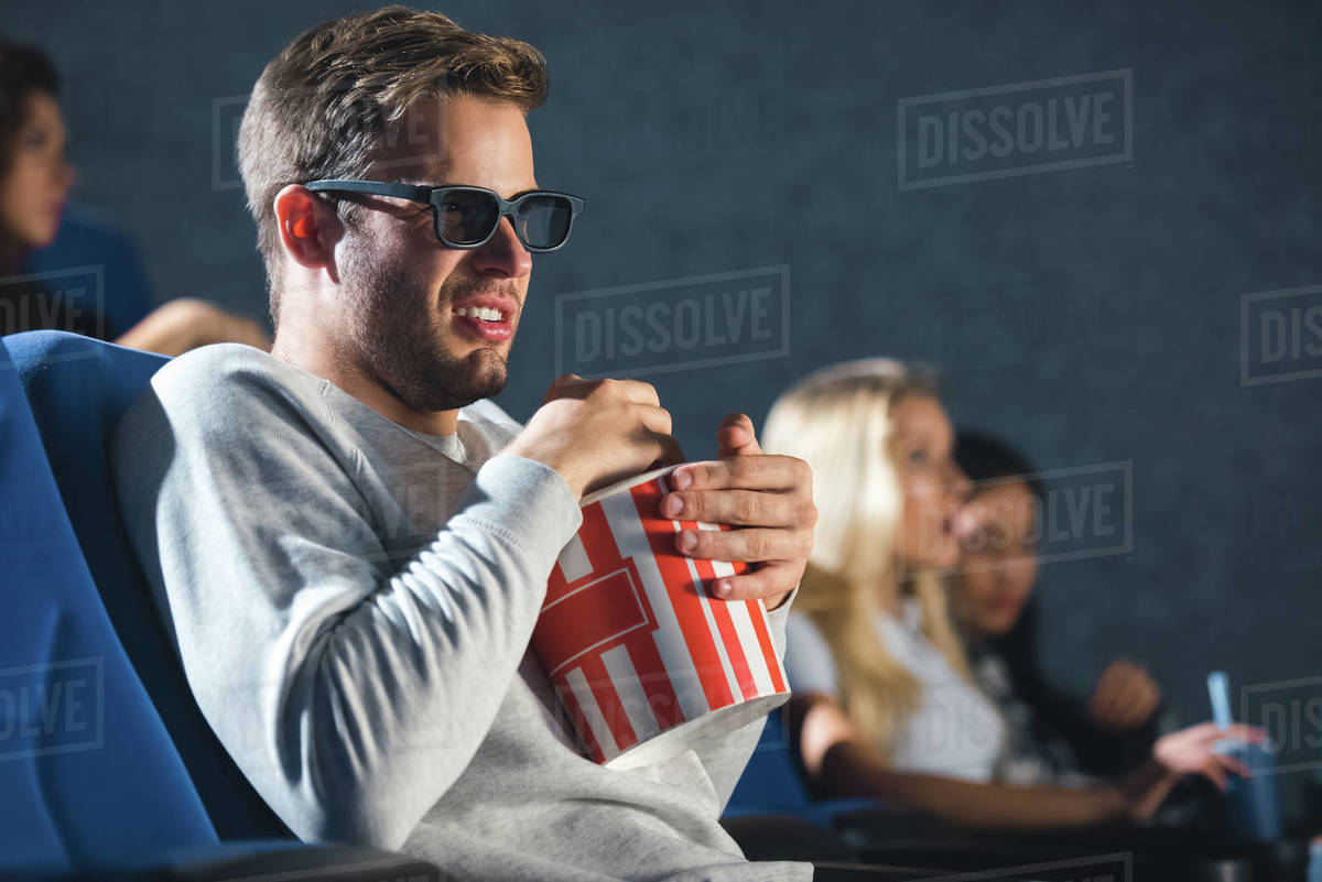 Side view of disgusted man in 3d glasses with popcorn watching film in ...