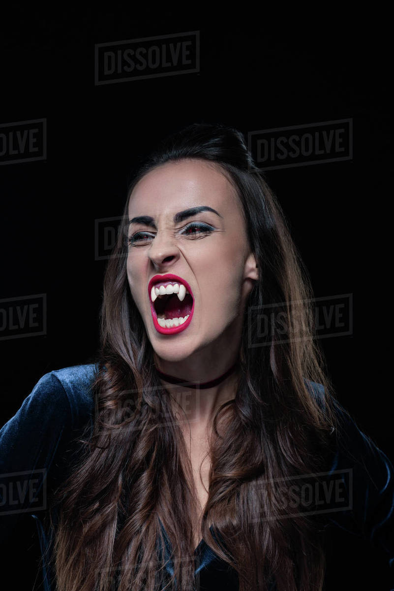 Beautiful woman showing vampire teeth isolated on black - Stock Photo ...