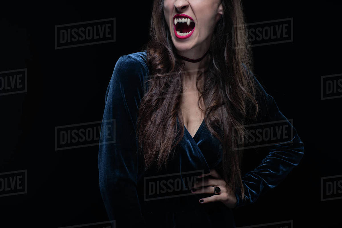 Cropped view of woman showing vampire teeth isolated on black - Stock ...