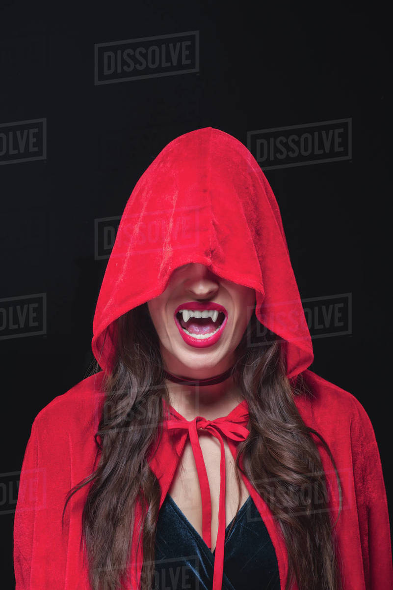 Vampire woman in red cloak showing her fangs isolated on black ...