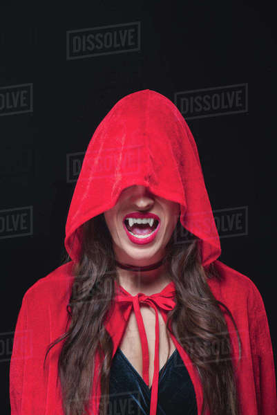 Vampire woman in red cloak showing her fangs isolated on black ...