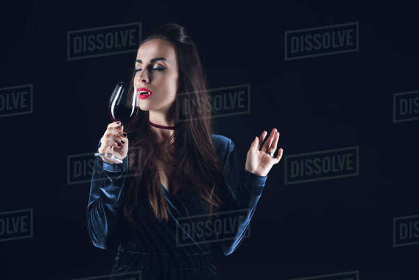 Beautiful vampire drinking blood from wineglass isolated on black ...